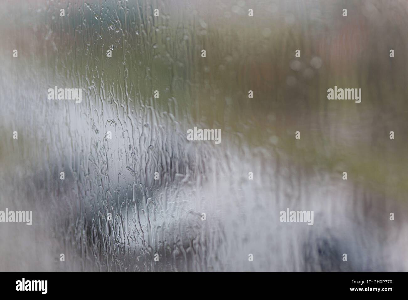 Rainy day through the window on cloudy grey sky and city buildings ...
