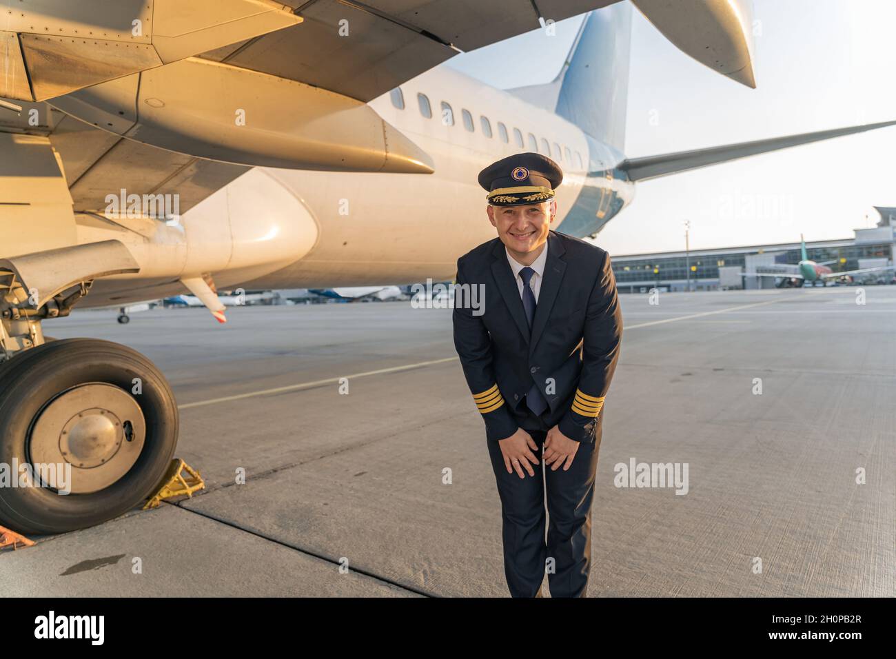 Happy pilot posing under the wing of an airplane Stock Photo - Alamy