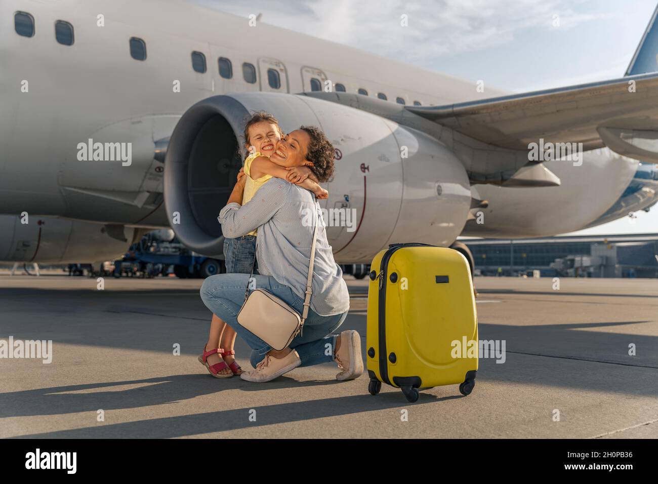Smiling adult lady hugging her child near the plane outdoor Stock Photo ...
