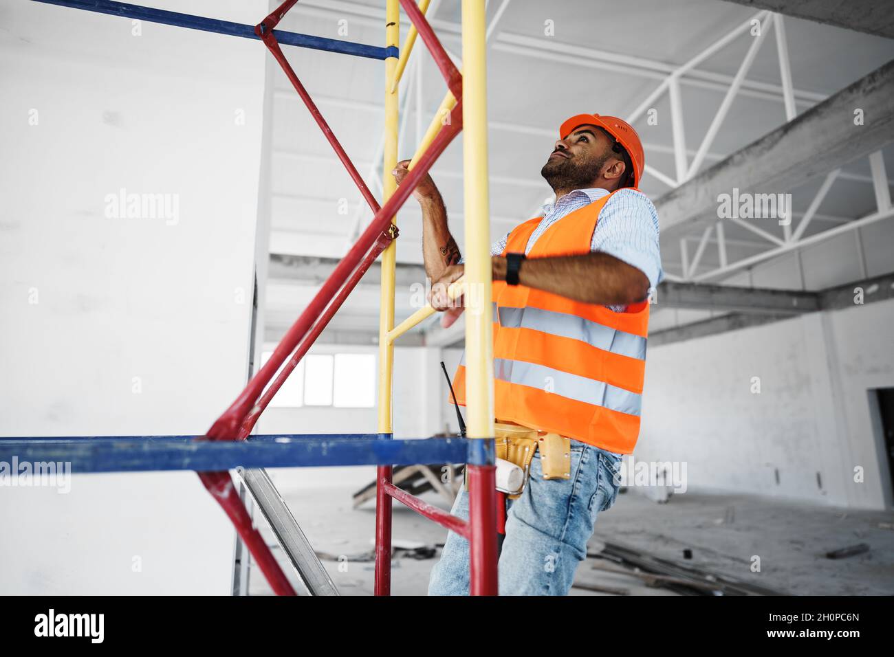 Young handsome builder climbing on scaffolding at construction site ...