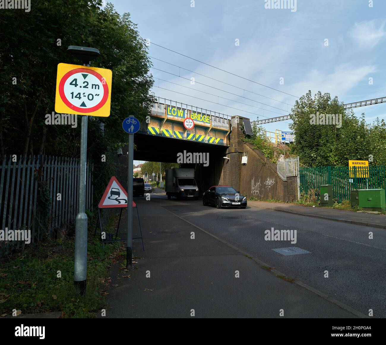 Vehicles on a road under a low railway bridge bridge, maximum height of ...