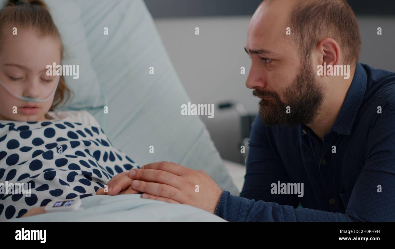 Worried emotional father crying beside sick daughter waiting for ...
