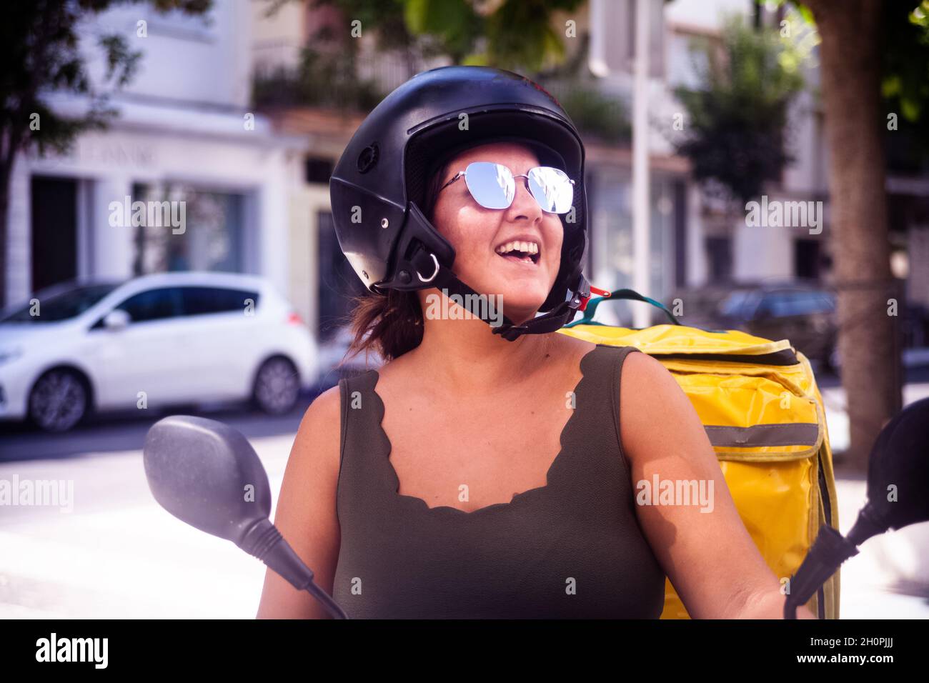 Female courier in a black helmet delivering food on a scooter Stock ...