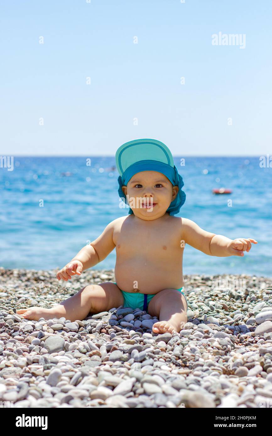 Sweet chubby baby on pebble beach. Blue sea and summer sunshine Stock ...