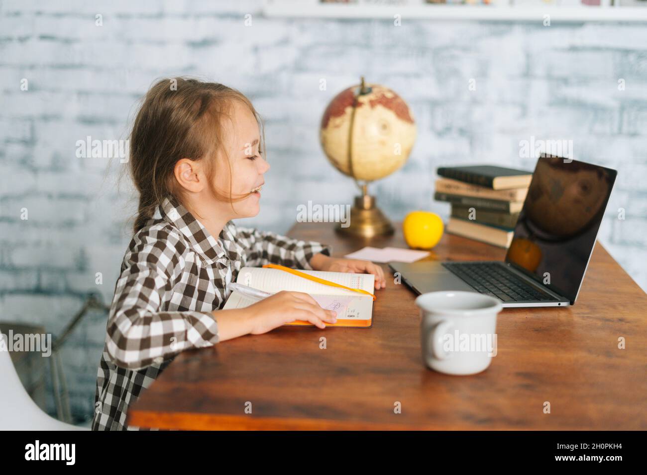 Side view of positive cheerful pupil child school girl doing homework ...