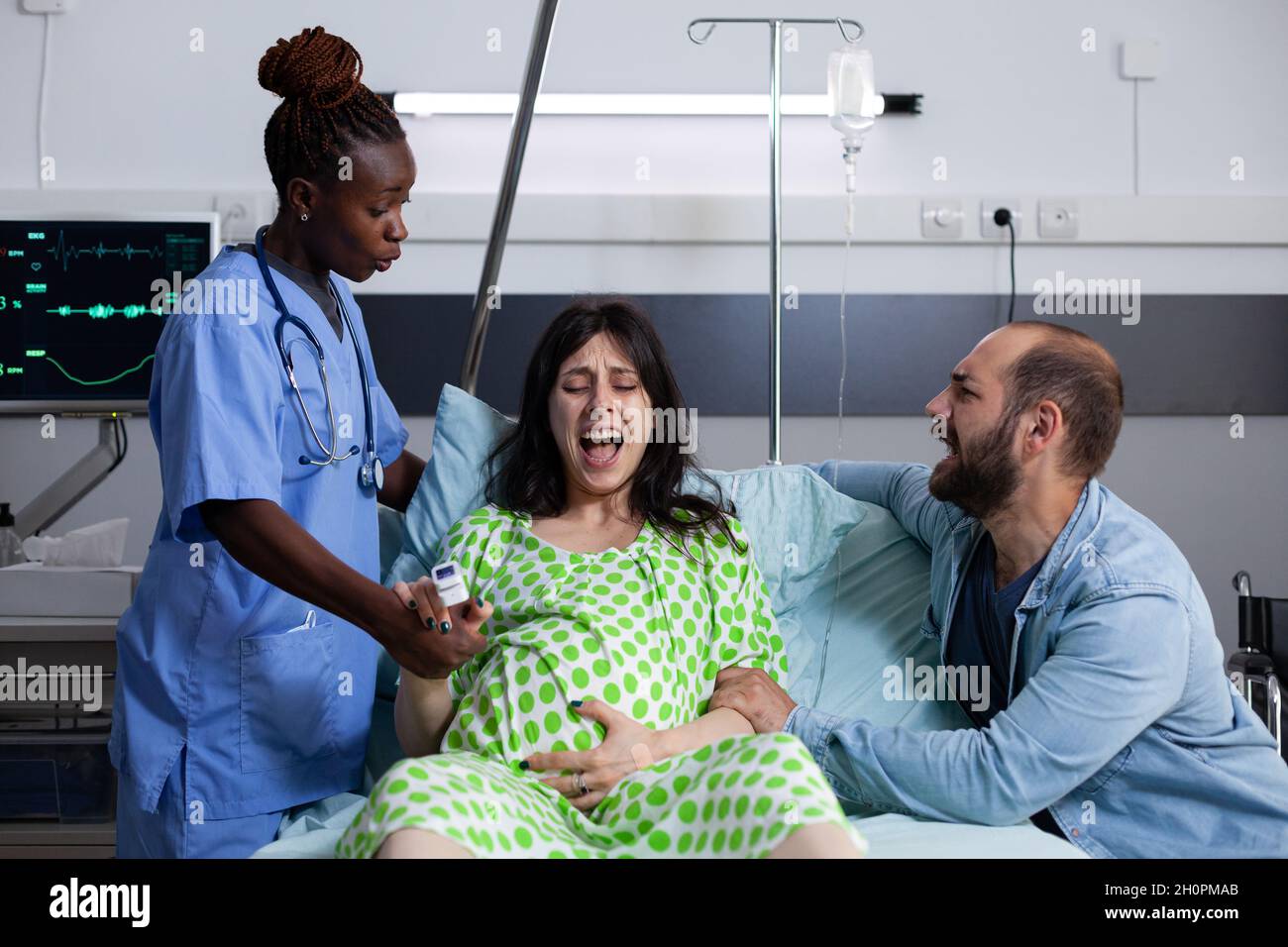 Young woman in labor screaming from contractions sitting in hospital ...