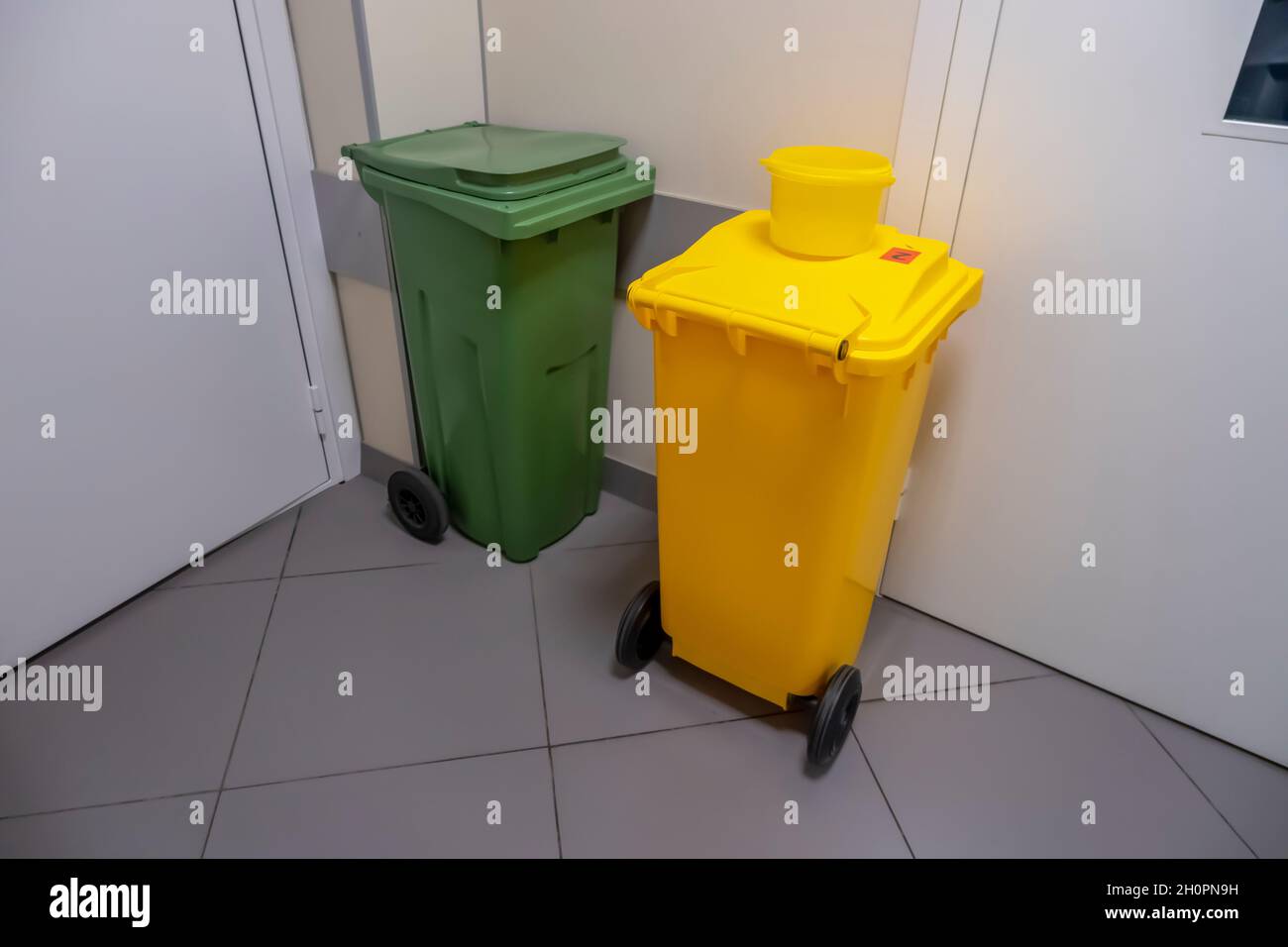 two dumpsters of different colors are in the corner of the room Stock ...