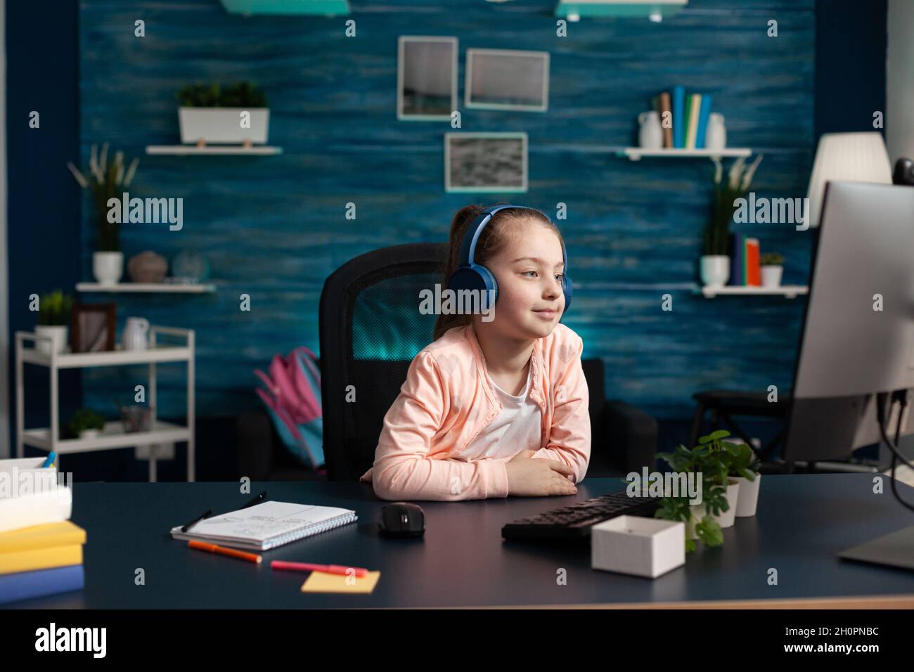 Little child wearing headphones having online math lesson on computer ...