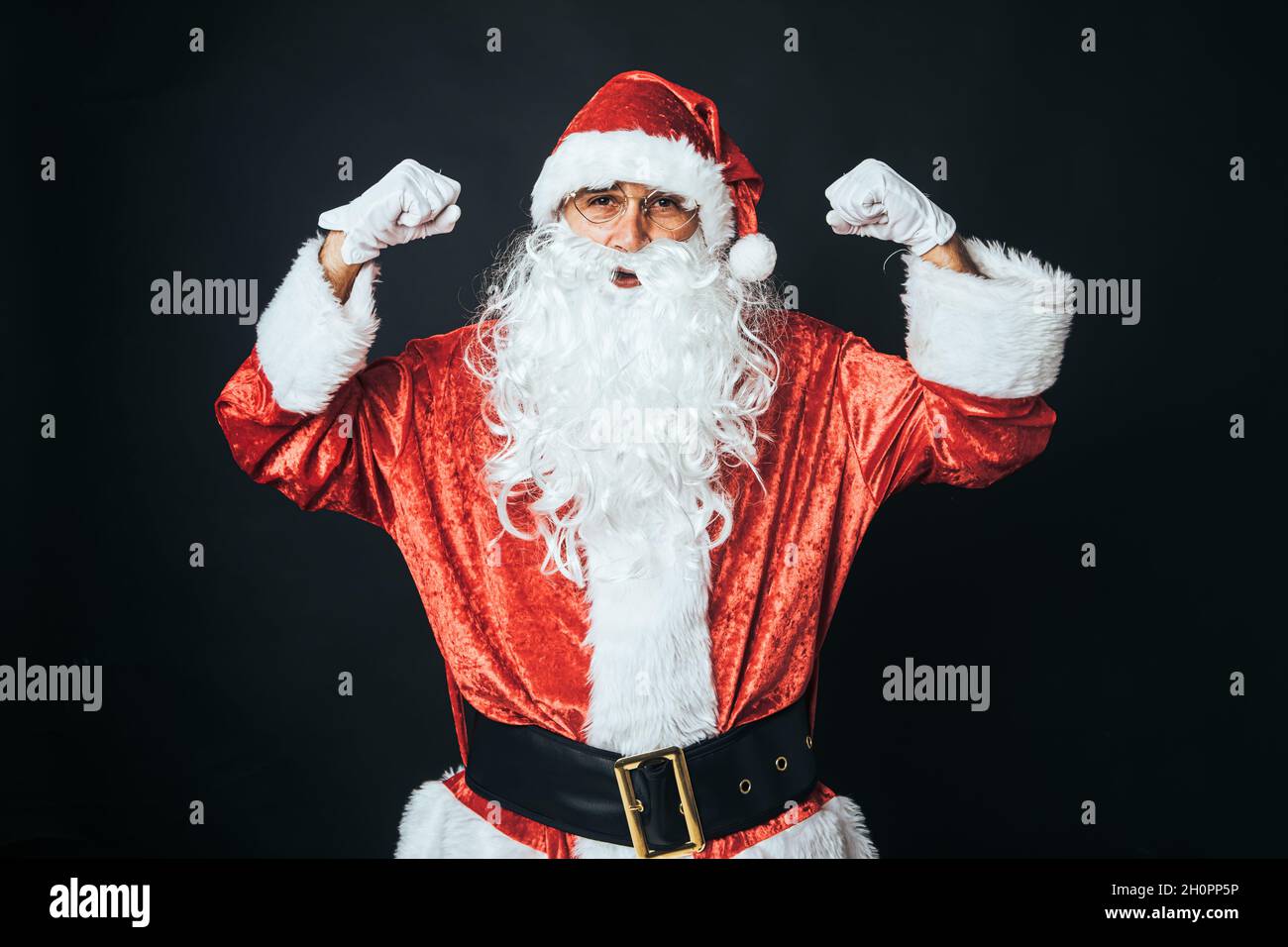 Man dressed as Santa Claus sticking out biceps with both arms as a sign ...