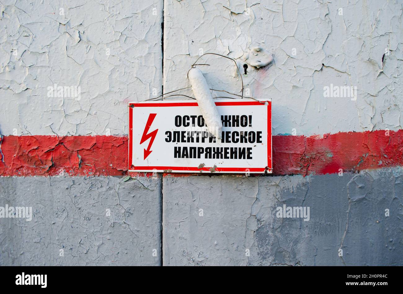 Caution. High voltage. Red warning sign on a metal door. In Russian ...