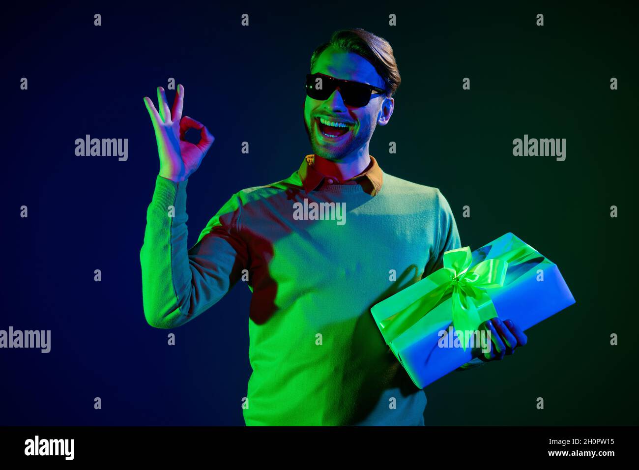 Photo of young cool millennial guy hold present show okey wear ...