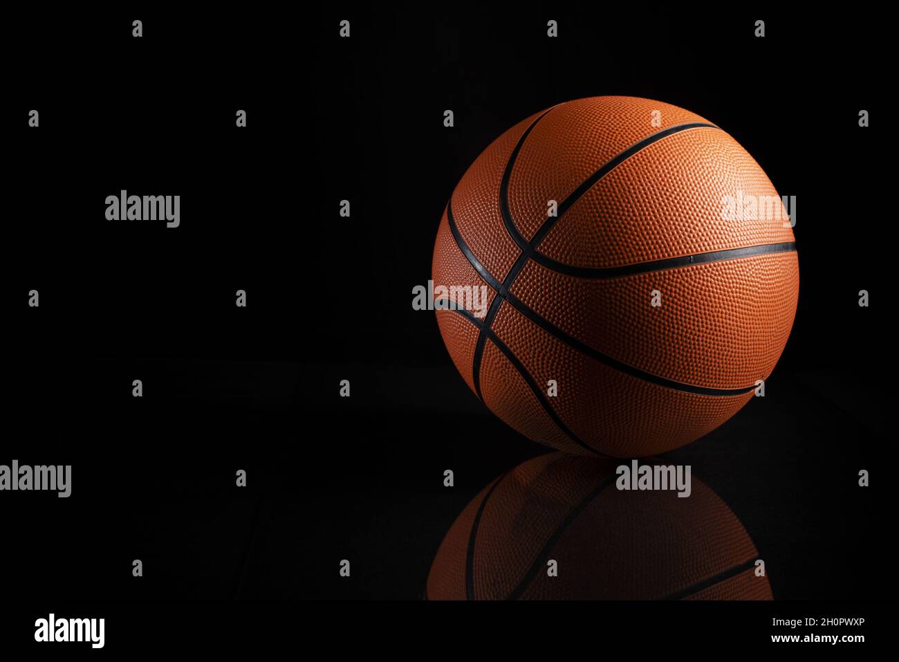 Closeup shot of a brown basketball ball with black stripes on a black ...