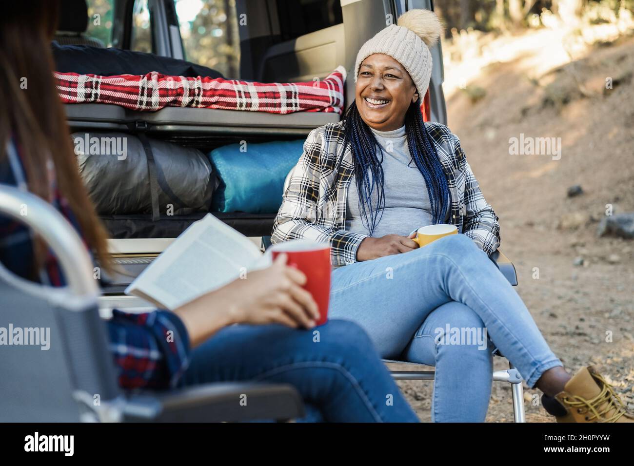 Multiracial women friends having fun camping with camper van outdoor in ...