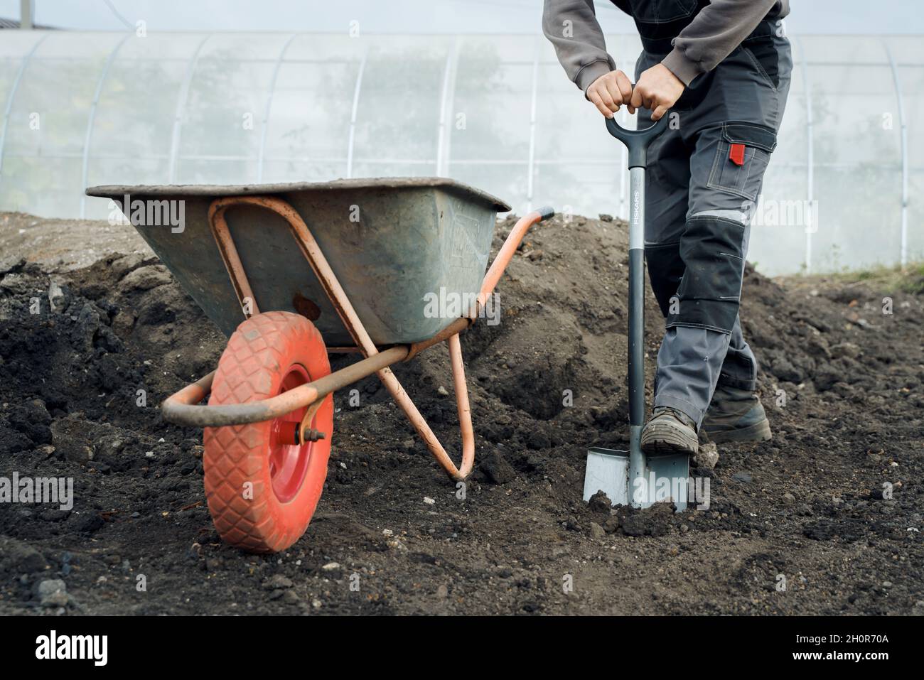 Working with garden tools, shovel and wheelbarrow on the site of a ...