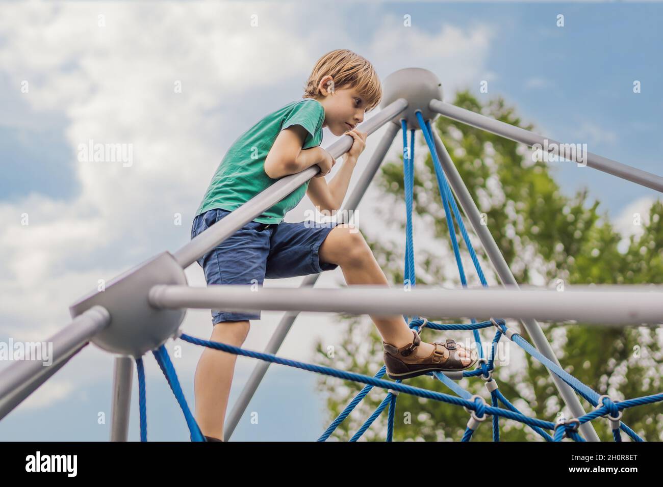 Young boy on climbing rope in playground Stock Photo - Alamy