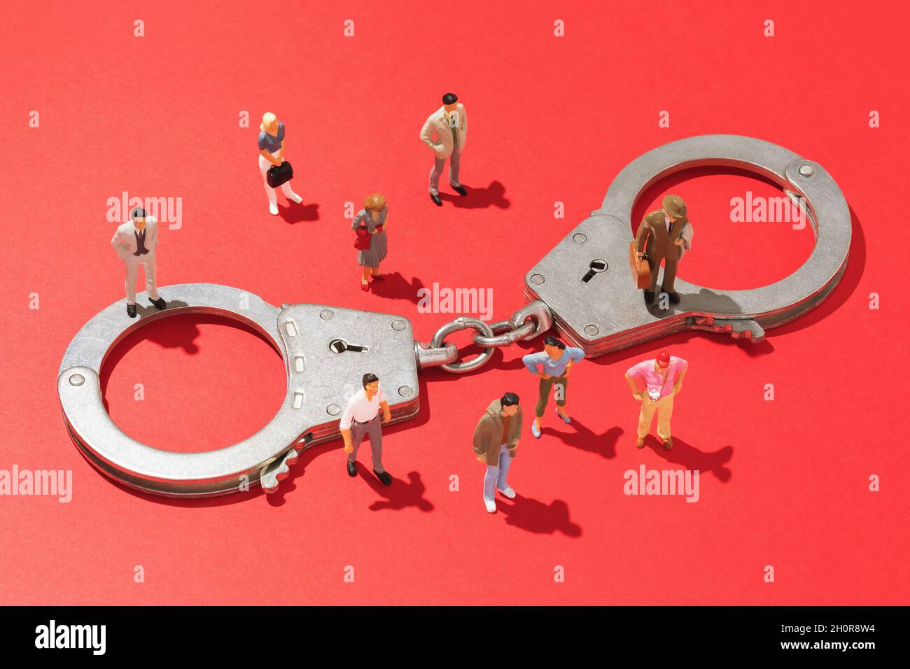 Handcuffs and toy men made of plastic on a red background, a concept on ...