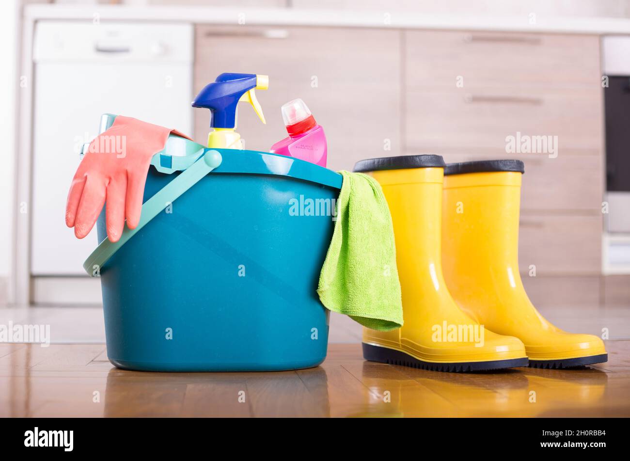 Cleaning products and tools on kitchen floor with cabinets in ...