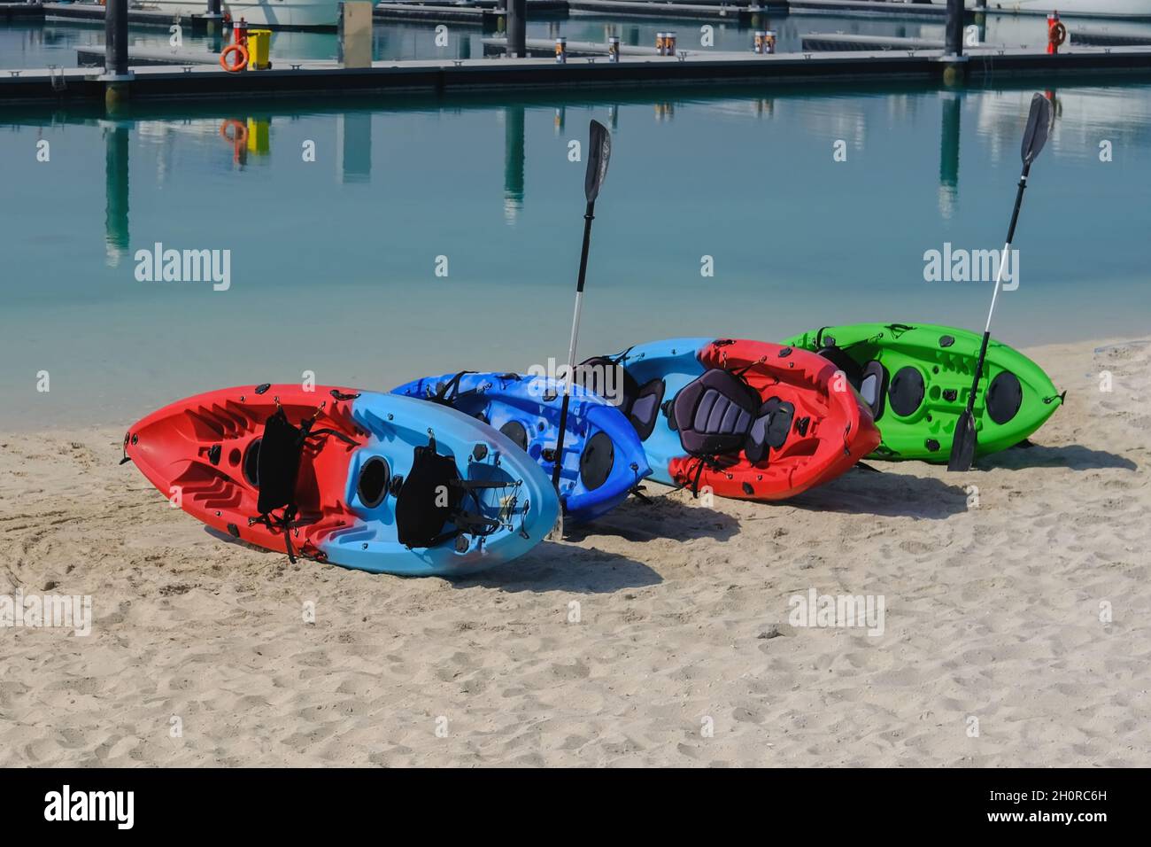 Colorful kayaks lying orderly on sandy beach at sport recreation area ...