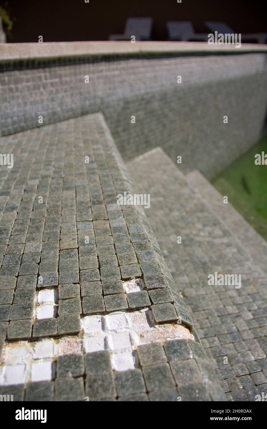 Missing tiles in a grey mosaic abandoned swimming pool Stock Photo - Alamy