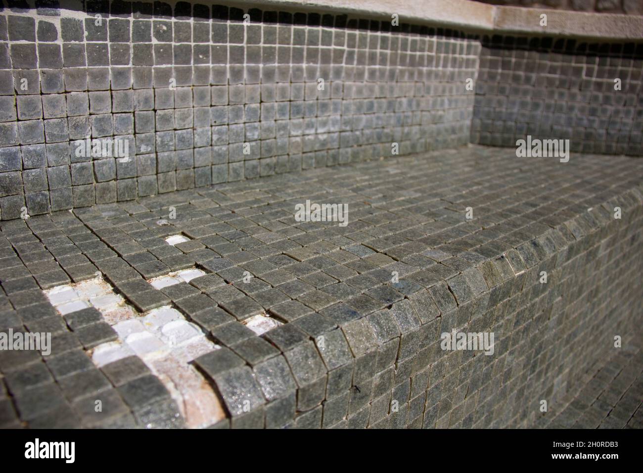 Missing tiles in a grey mosaic abandoned swimming pool Stock Photo - Alamy