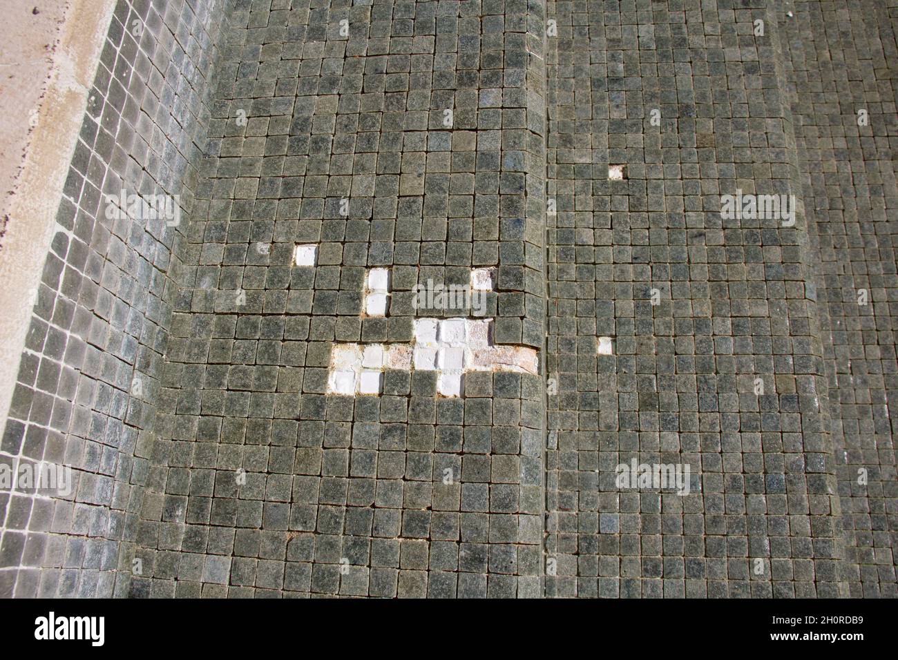 Missing tiles in a grey mosaic abandoned swimming pool Stock Photo - Alamy