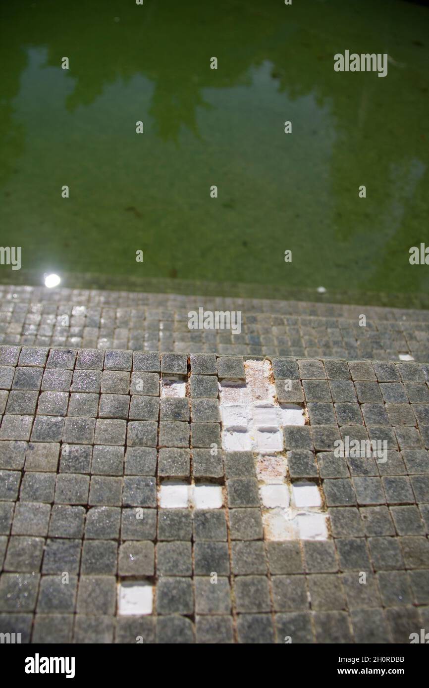 Missing tiles in a grey mosaic abandoned swimming pool Stock Photo - Alamy