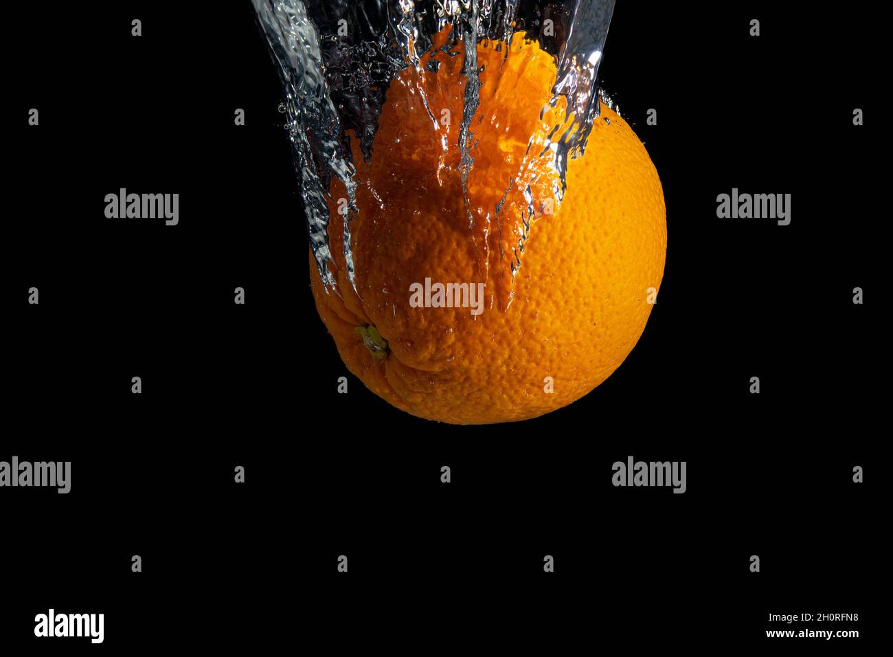 Fresh whole orange fruit in water splash isolated on black background ...