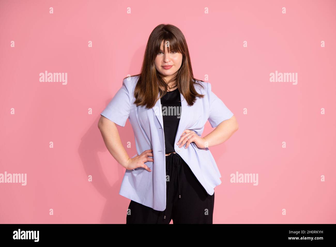 Portrait of dark-haired girl snapping. Stands, hands on waist looks ...