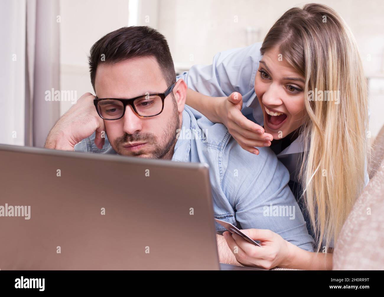 Young couple shopping online, lying on sofa and looking at laptop at ...