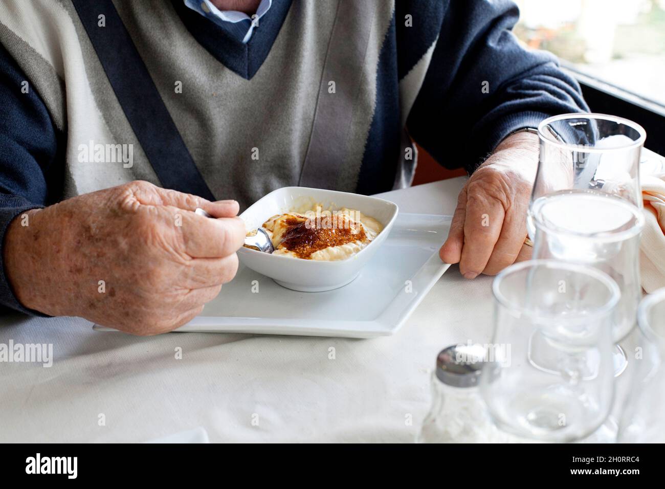 Man sitting at a table eating traditional Turkish rice pudding dessert ...