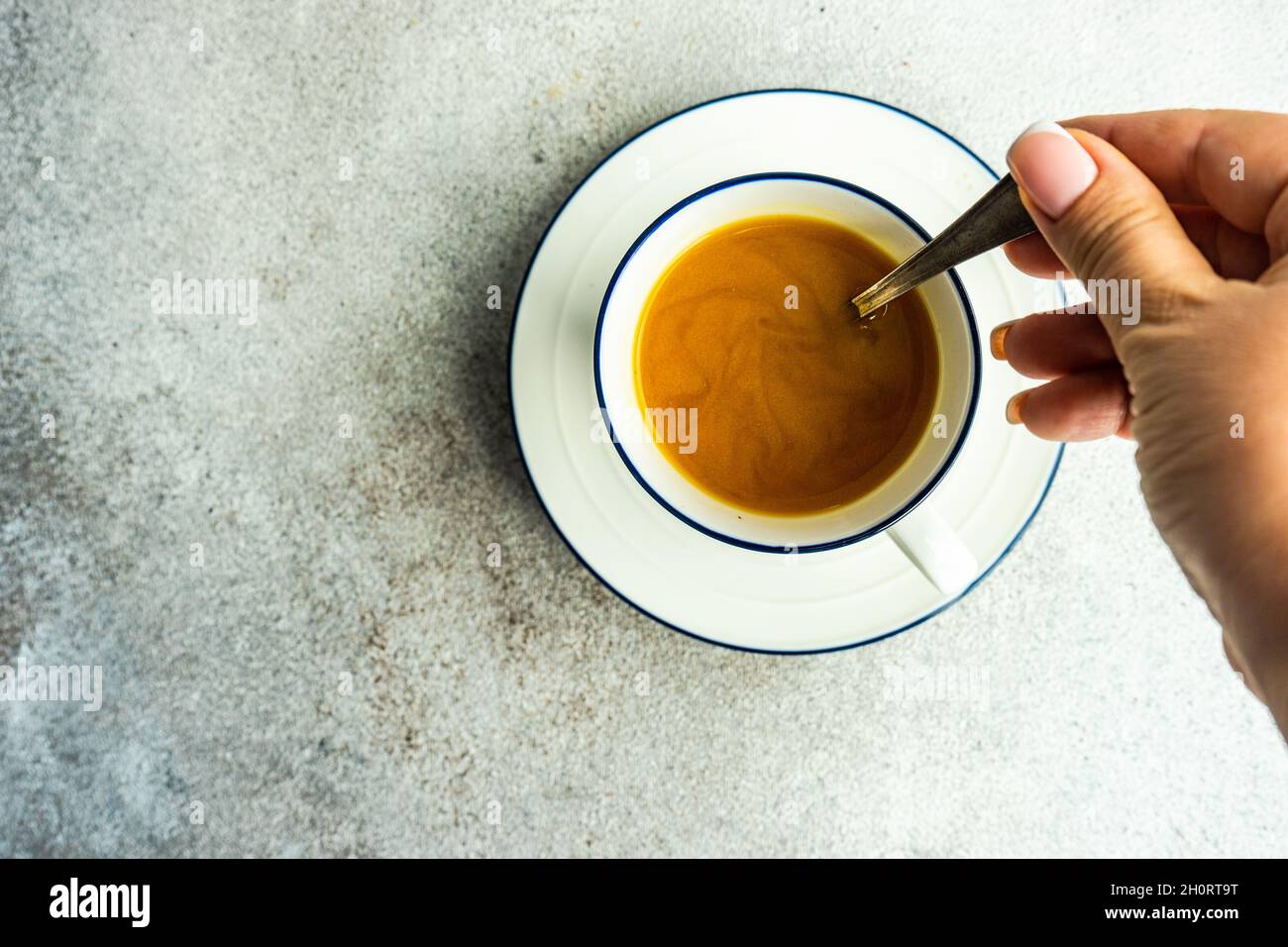 Overhead view of a woman stirring a cup of turmeric tea Stock Photo - Alamy