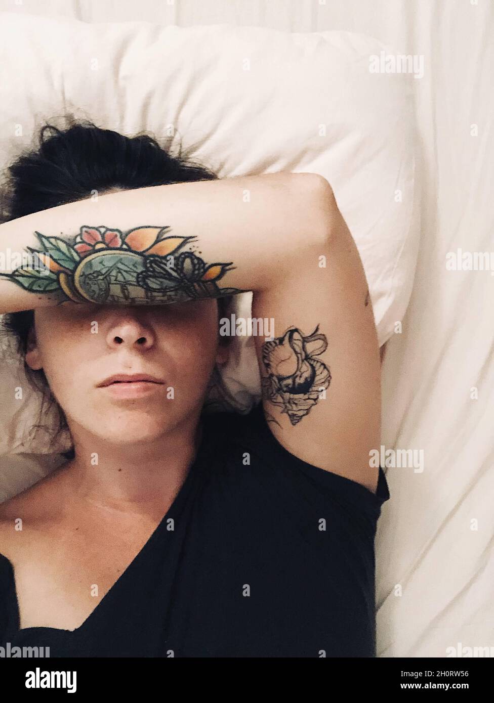 Overhead view of a woman lying in bed with her arm over her face Stock ...