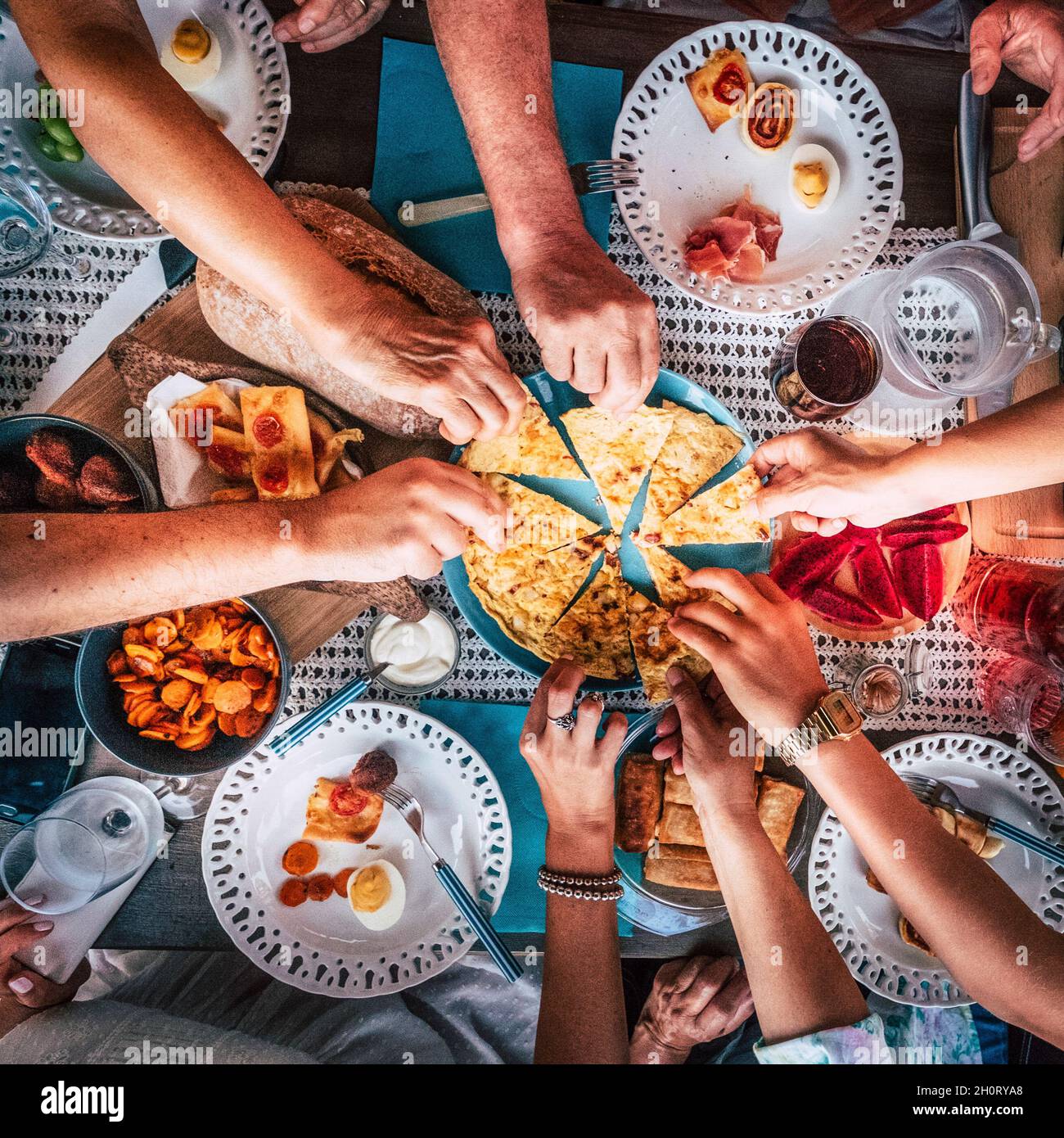 Above top view of hands picking food from the center of the table ...
