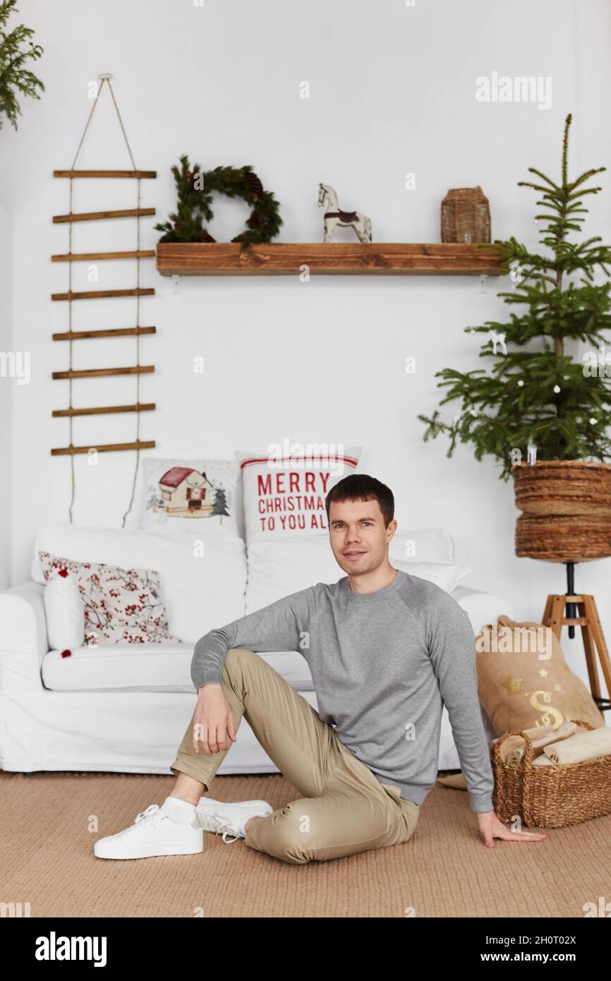 Handsome young man in casual outfit sitting on the floor in the living ...