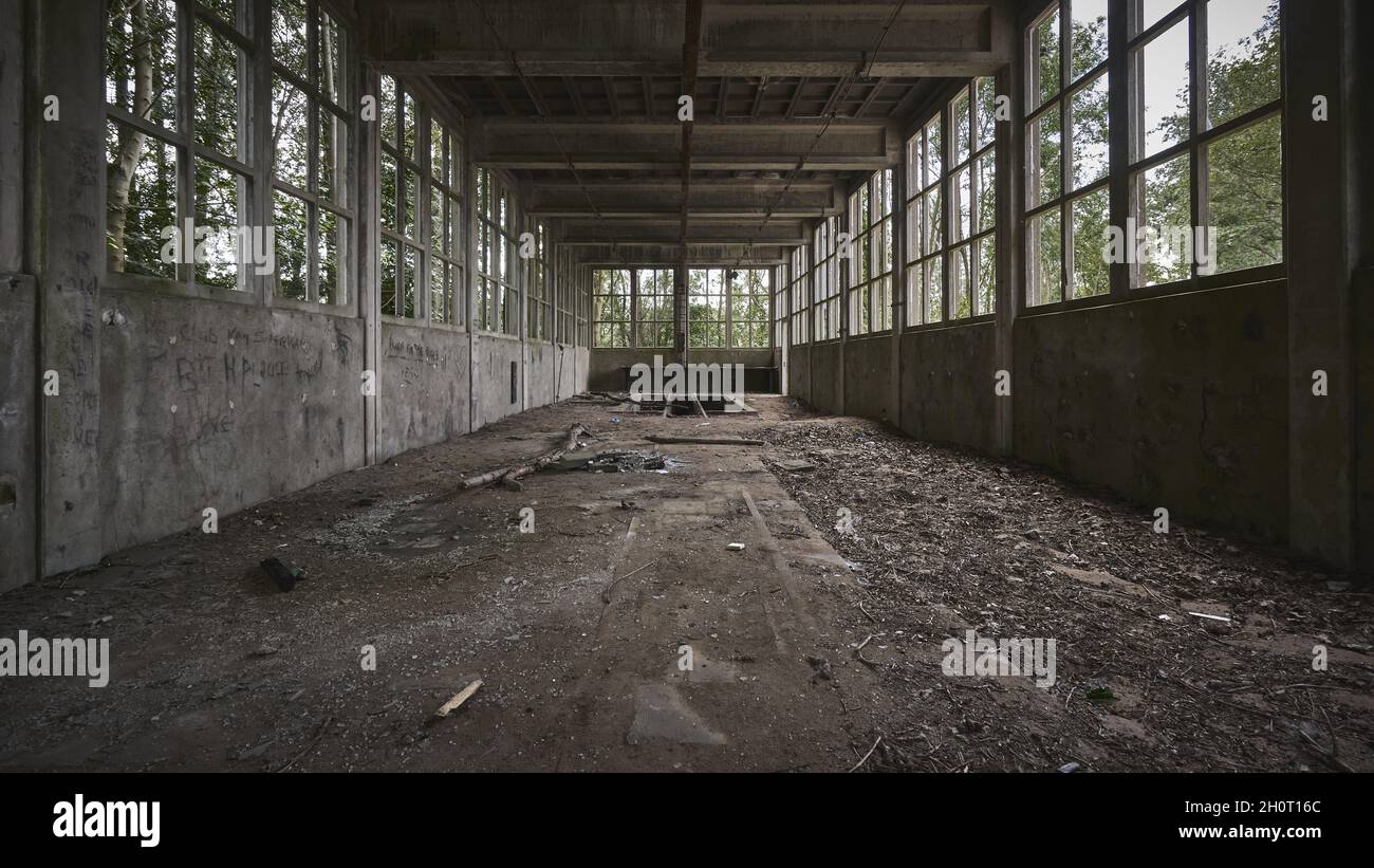 Hall of an old abandoned damaged weathered creepy building with windows ...