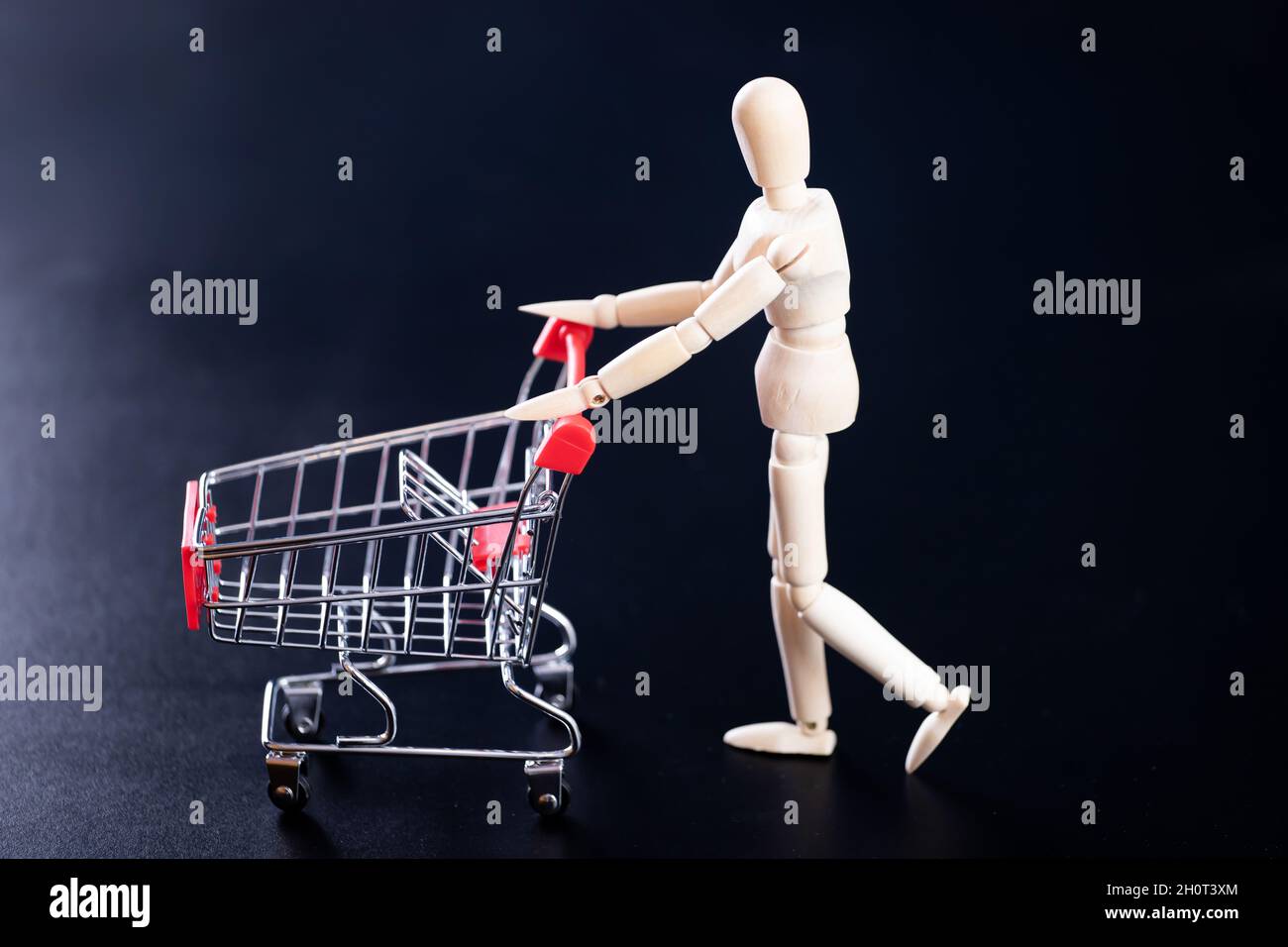 Go shopping concept. Wooden figure with shopping cart on blue ...