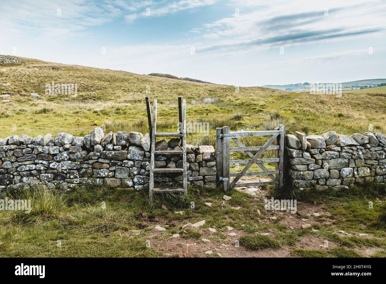 Traditional British stone wall with wooden ladder stile in countryside ...