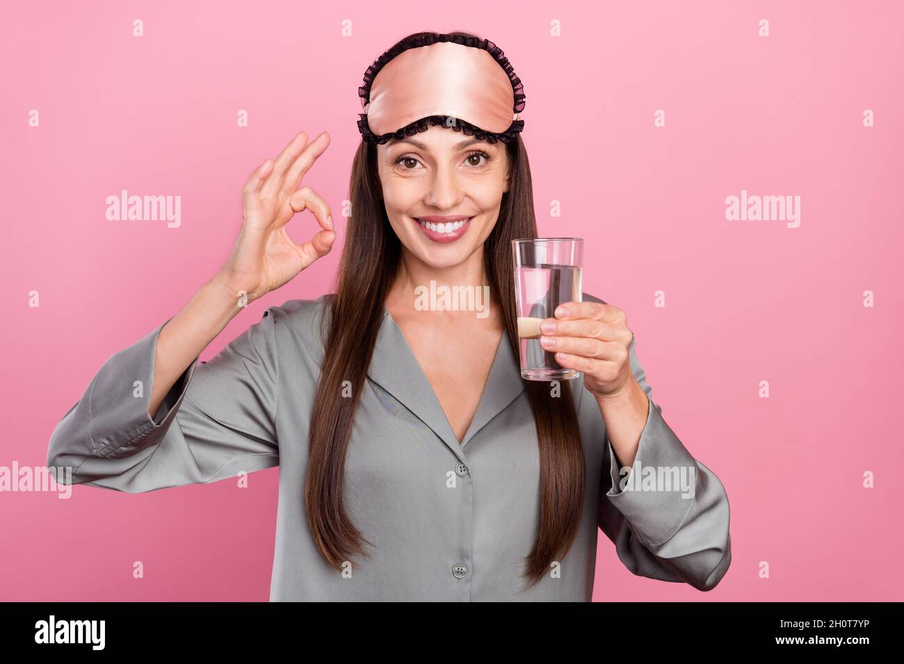 Portrait of attractive cheerful woman drinking water showing ok-sign ...