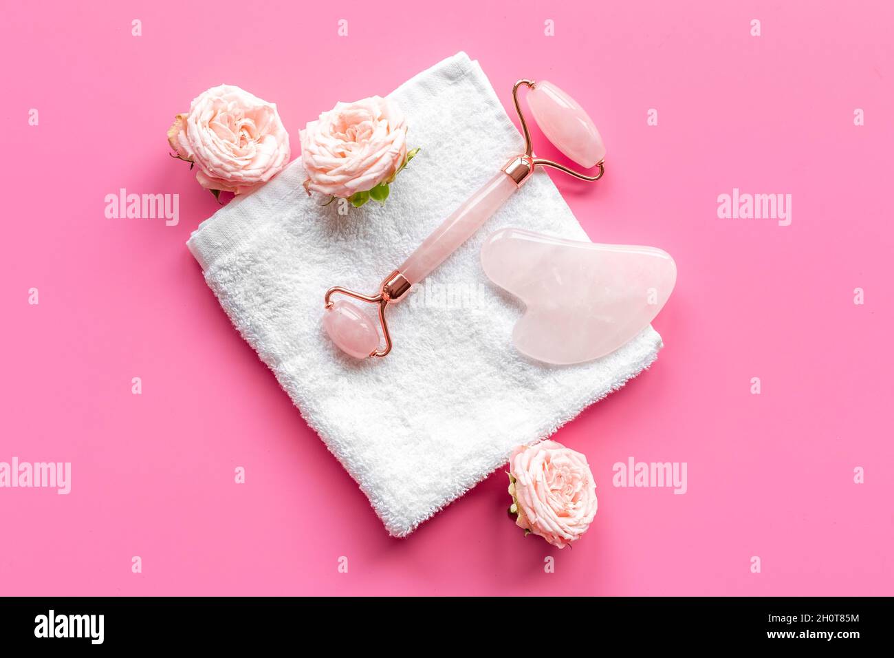 Pink gua sha massage stone and face roller with rose flowers Stock ...