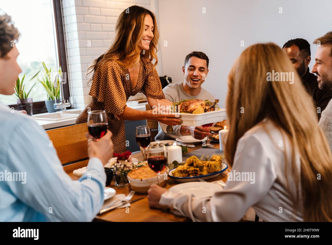 Multiracial happy friends eating turkey during thanksgiving dinner at ...