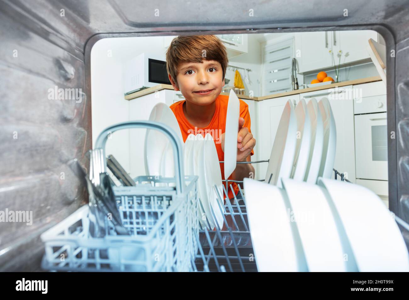 Kid smiling take plates from dishwashing machine Stock Photo - Alamy