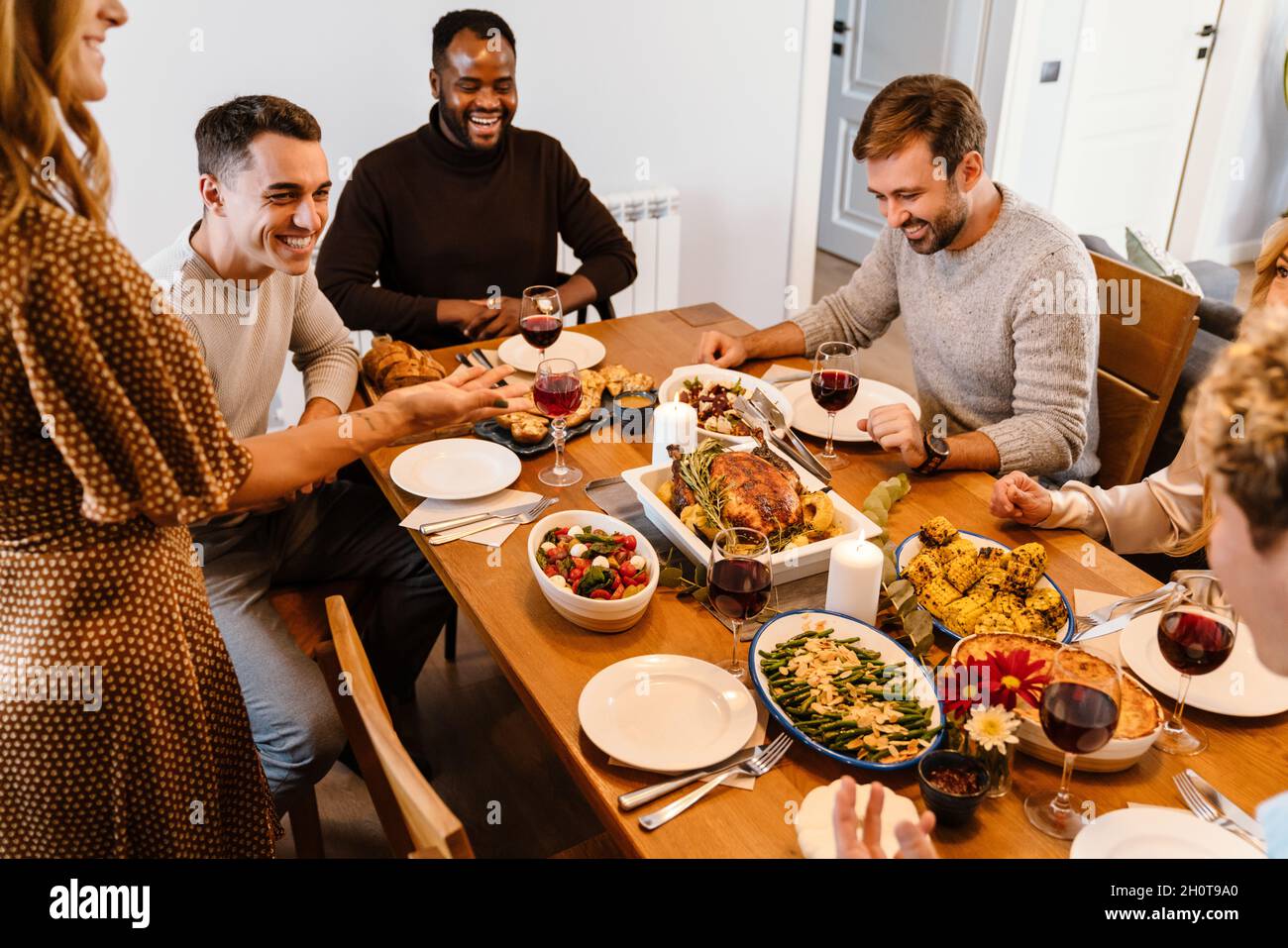 Multiracial happy friends eating turkey during thanksgiving dinner at ...