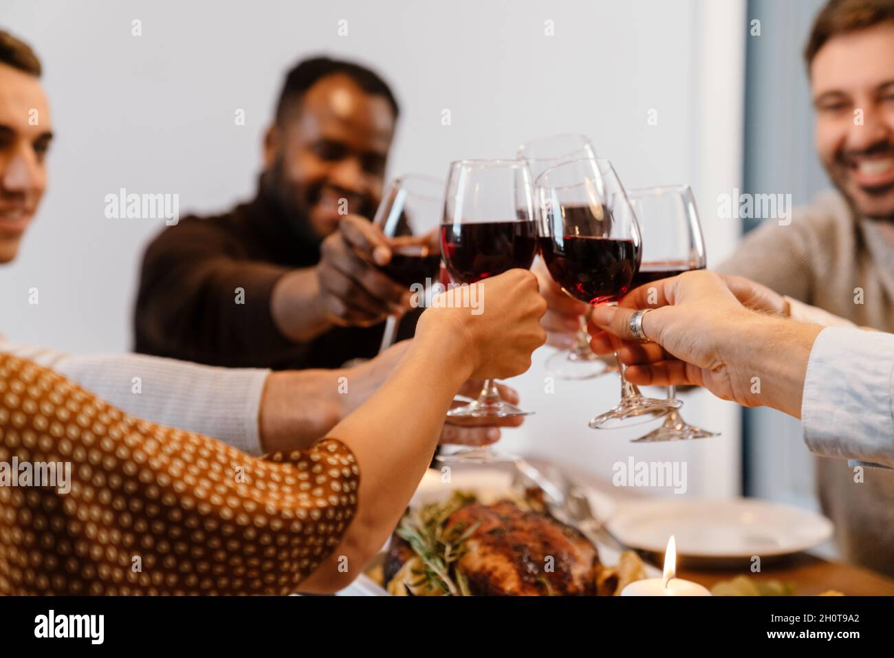Multiracial happy friends drinking wine during thanksgiving dinner at ...