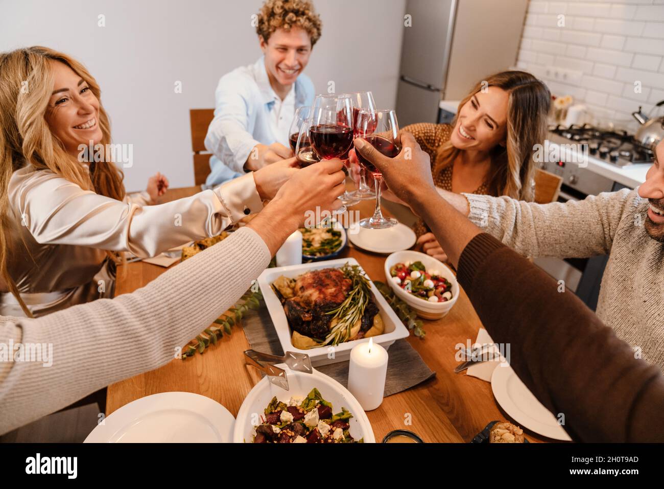 Multiracial happy friends drinking wine during thanksgiving dinner at ...