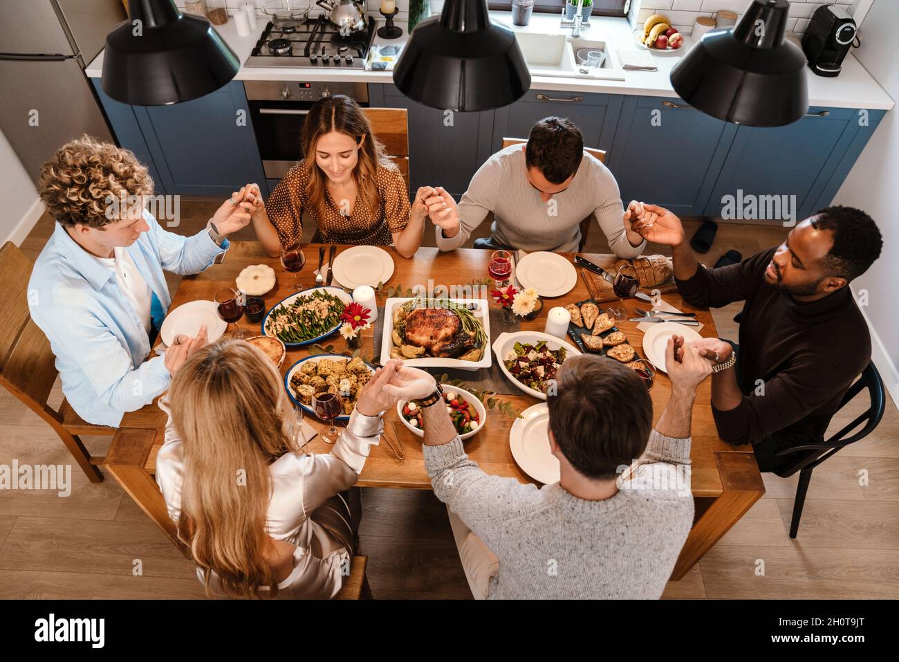 Multiracial friends holding hands and praying during thanksgiving ...