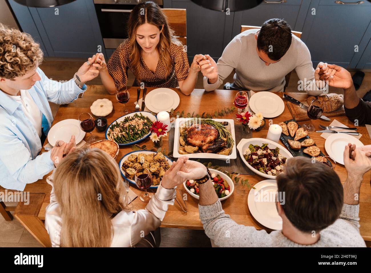Multiracial friends holding hands and praying during thanksgiving ...