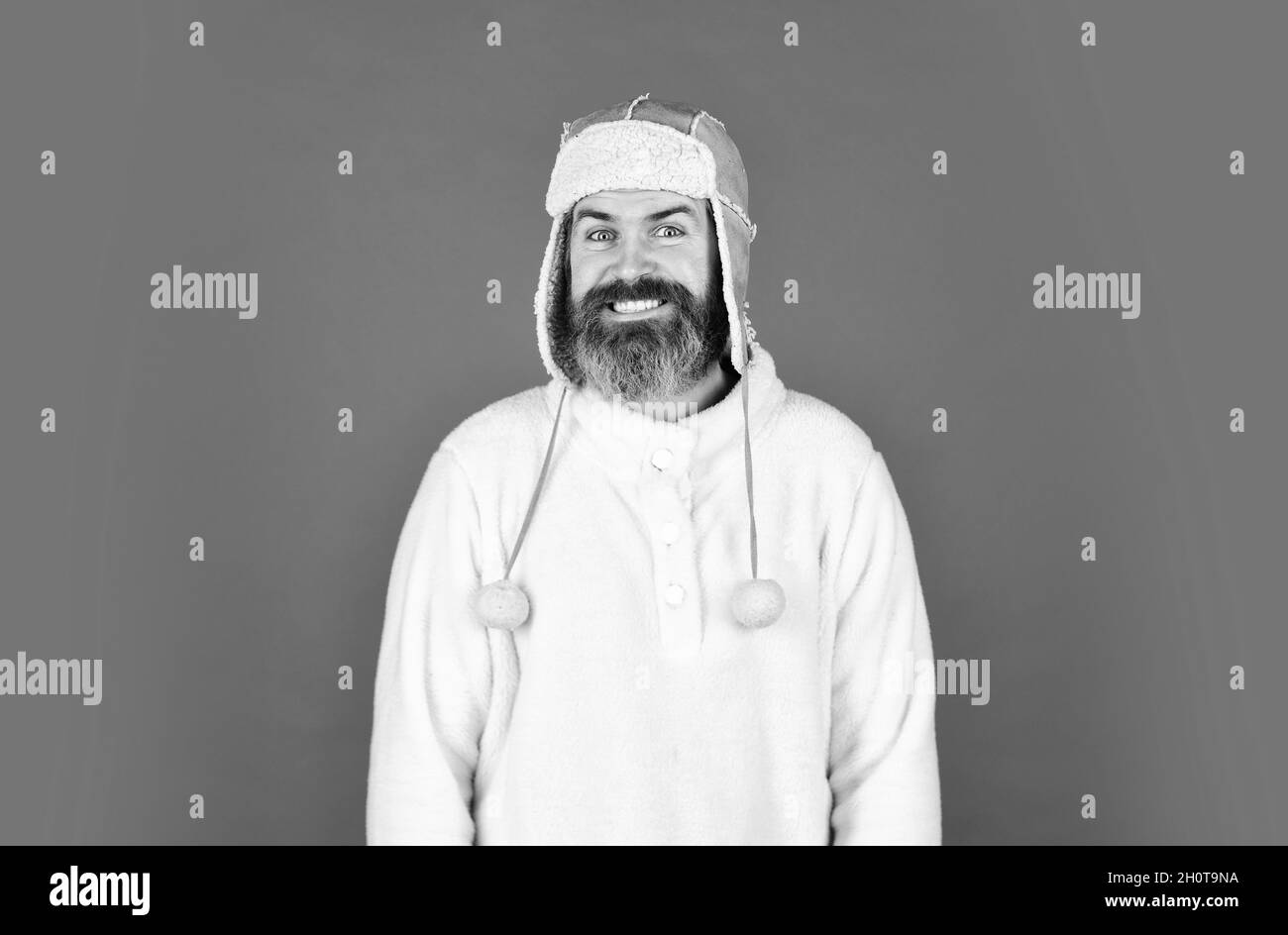 Bearded man wear hat with ear flaps red background. Soft furry ...