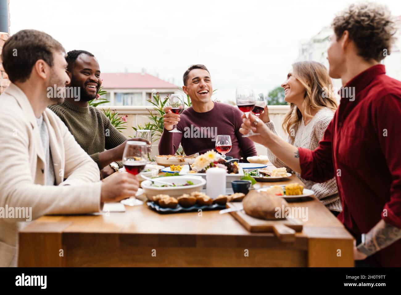 Multiracial happy friends drinking wine during thanksgiving dinner ...
