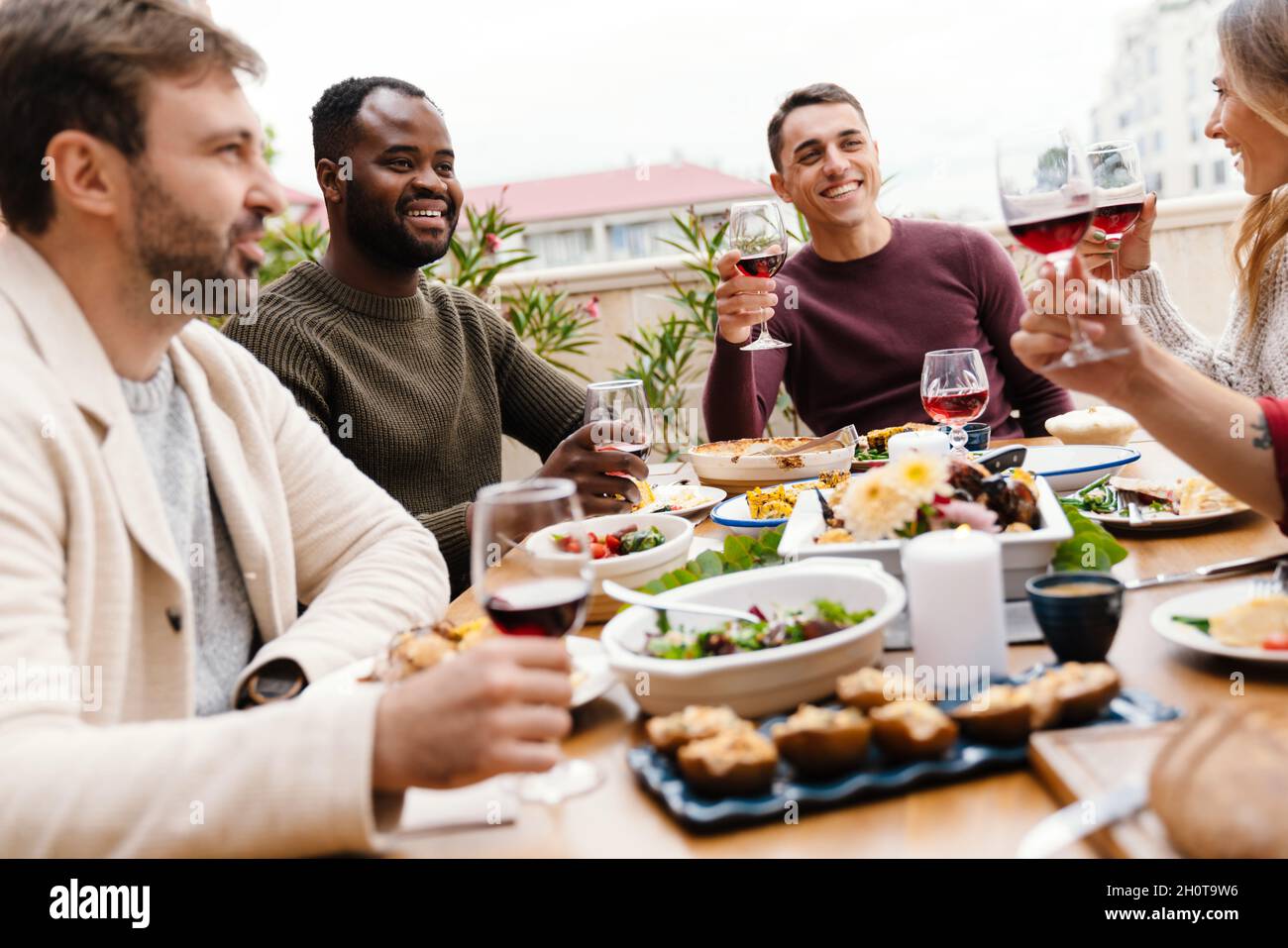 Multiracial happy friends drinking wine during thanksgiving dinner ...