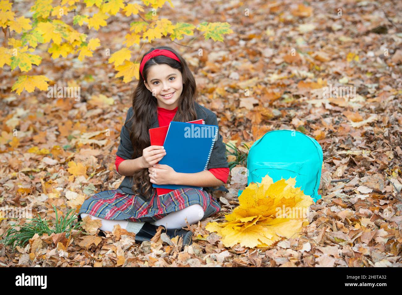 happy child with maple leaf bunch and backpack outdoor. autumn nature ...
